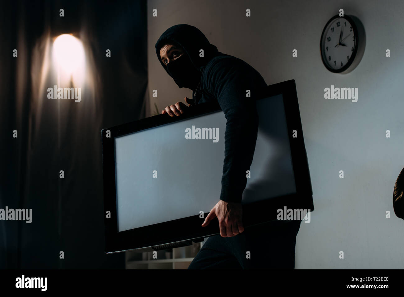 Robber in black mask stealing flat-screen tv with blank screen from ...