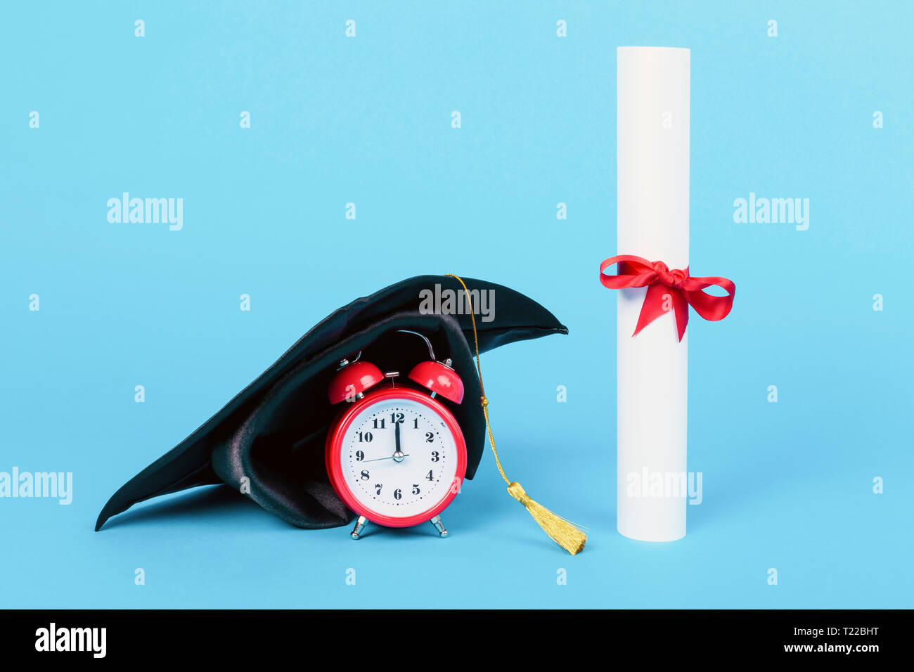 graduation cap on red clock near diploma, image on a blue background ...