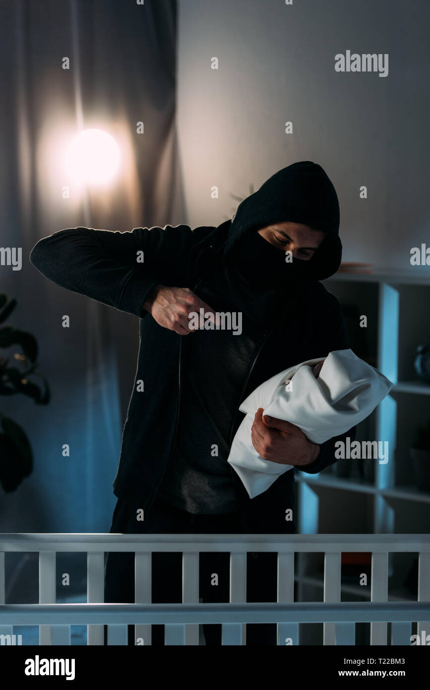 Kidnapper in black clothes aiming gun at infant child Stock Photo - Alamy