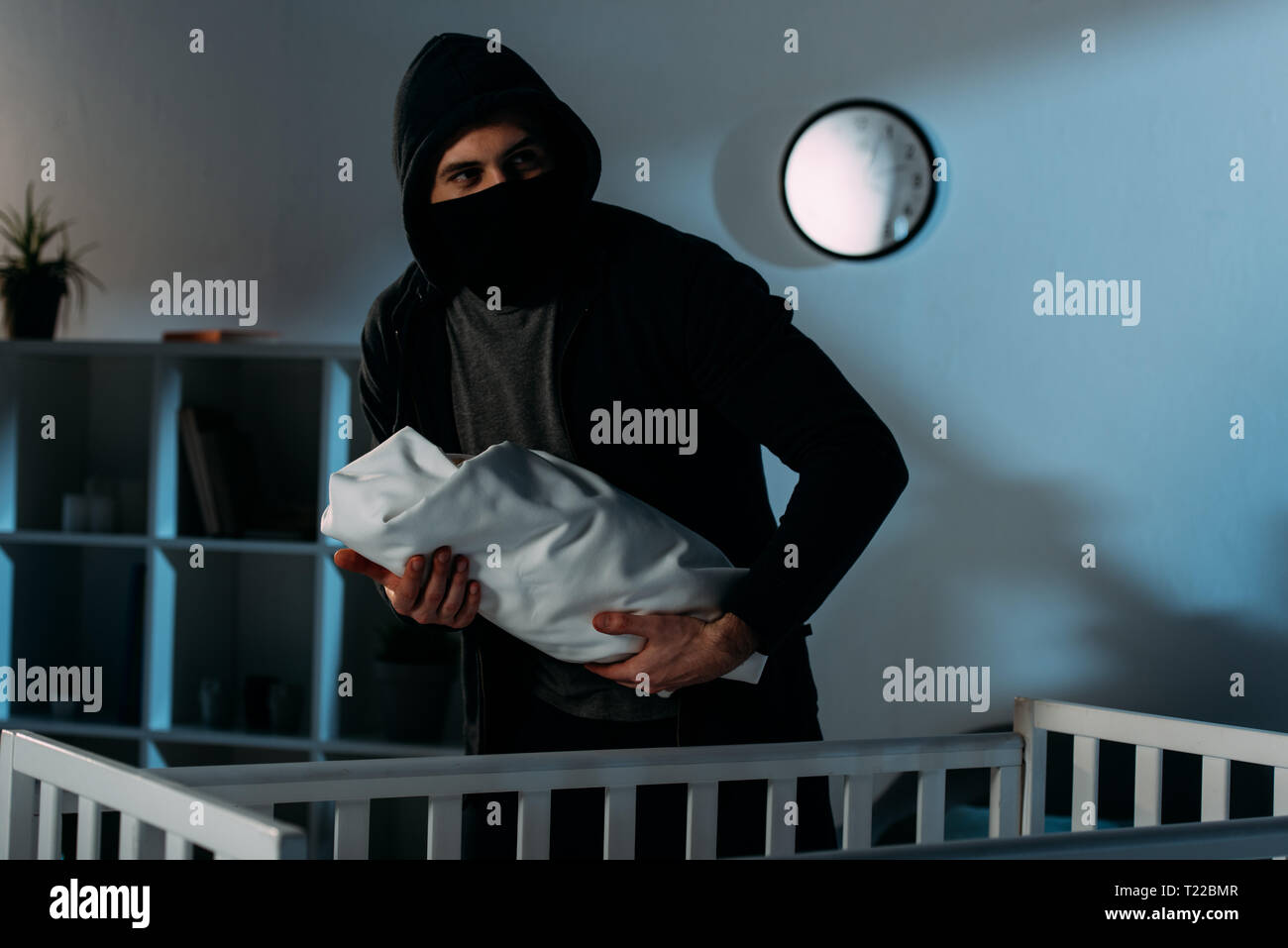 Kidnapper in black mask holding infant child near crib Stock Photo - Alamy