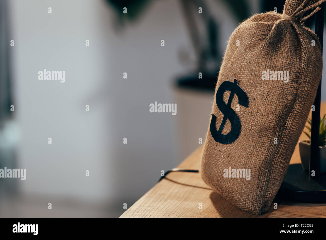 Money bag with dollar sign standing on wooden table Stock Photo - Alamy
