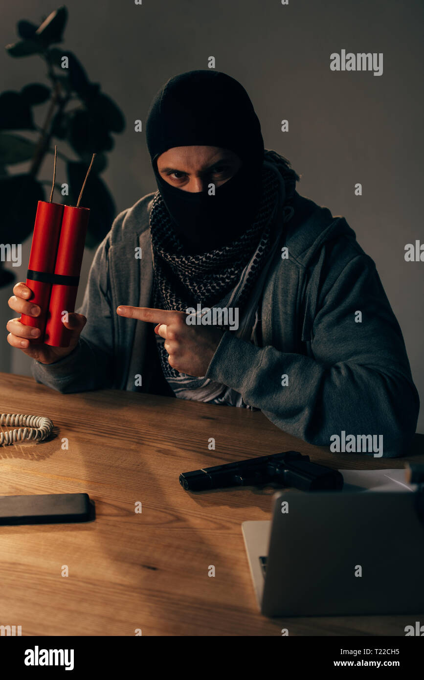 Angry terrorist in mask pointing with finger at dynamite in room Stock ...
