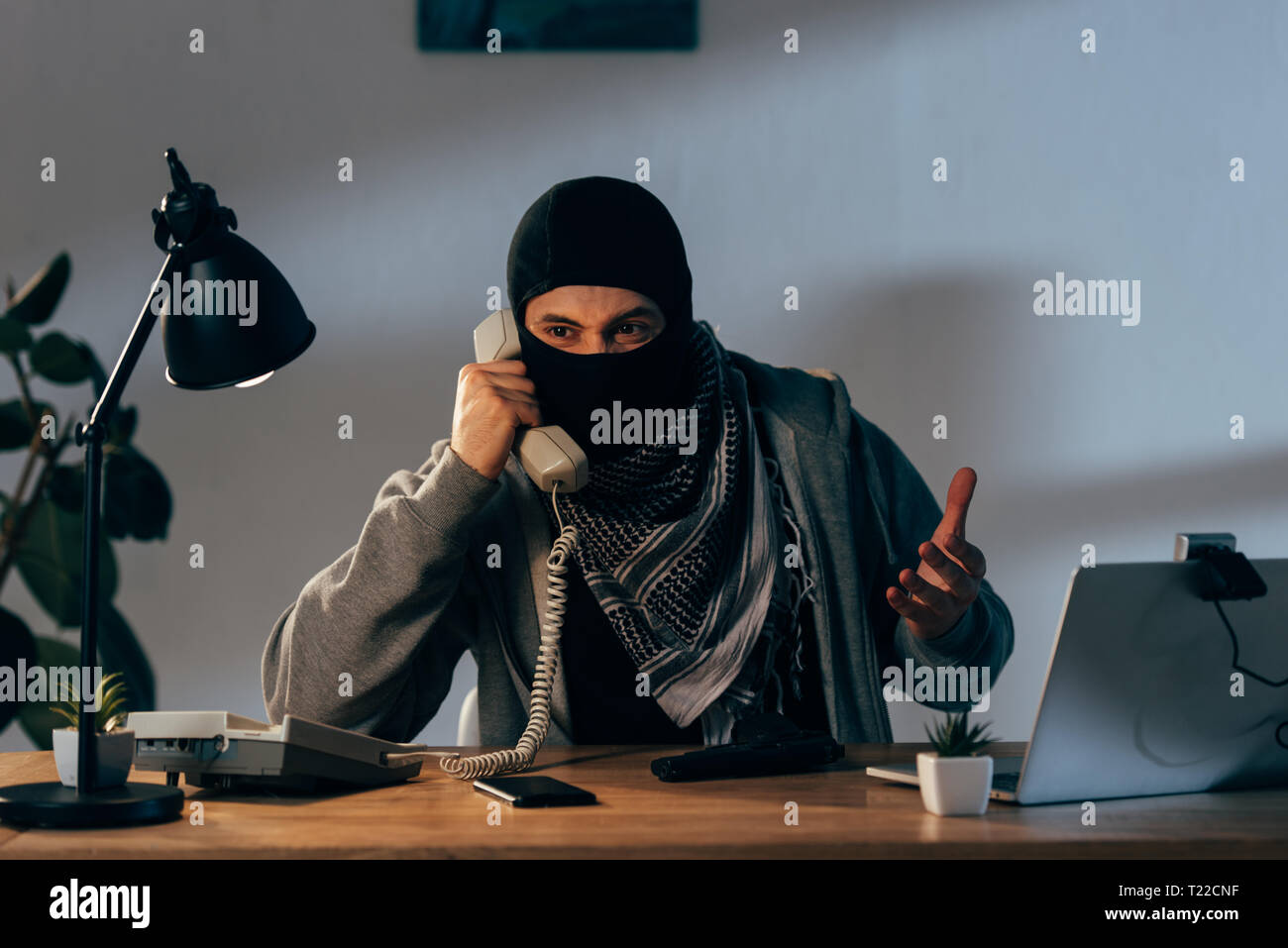 Angry terrorist in black mask talking on telephone in room Stock Photo ...