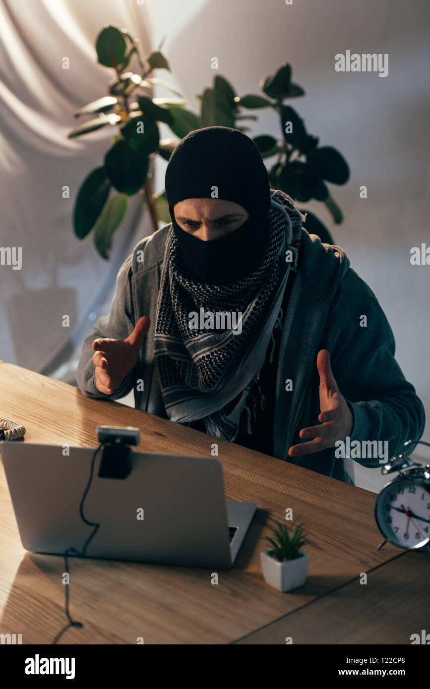 Angry criminal in mask gesturing at webcam in room Stock Photo - Alamy