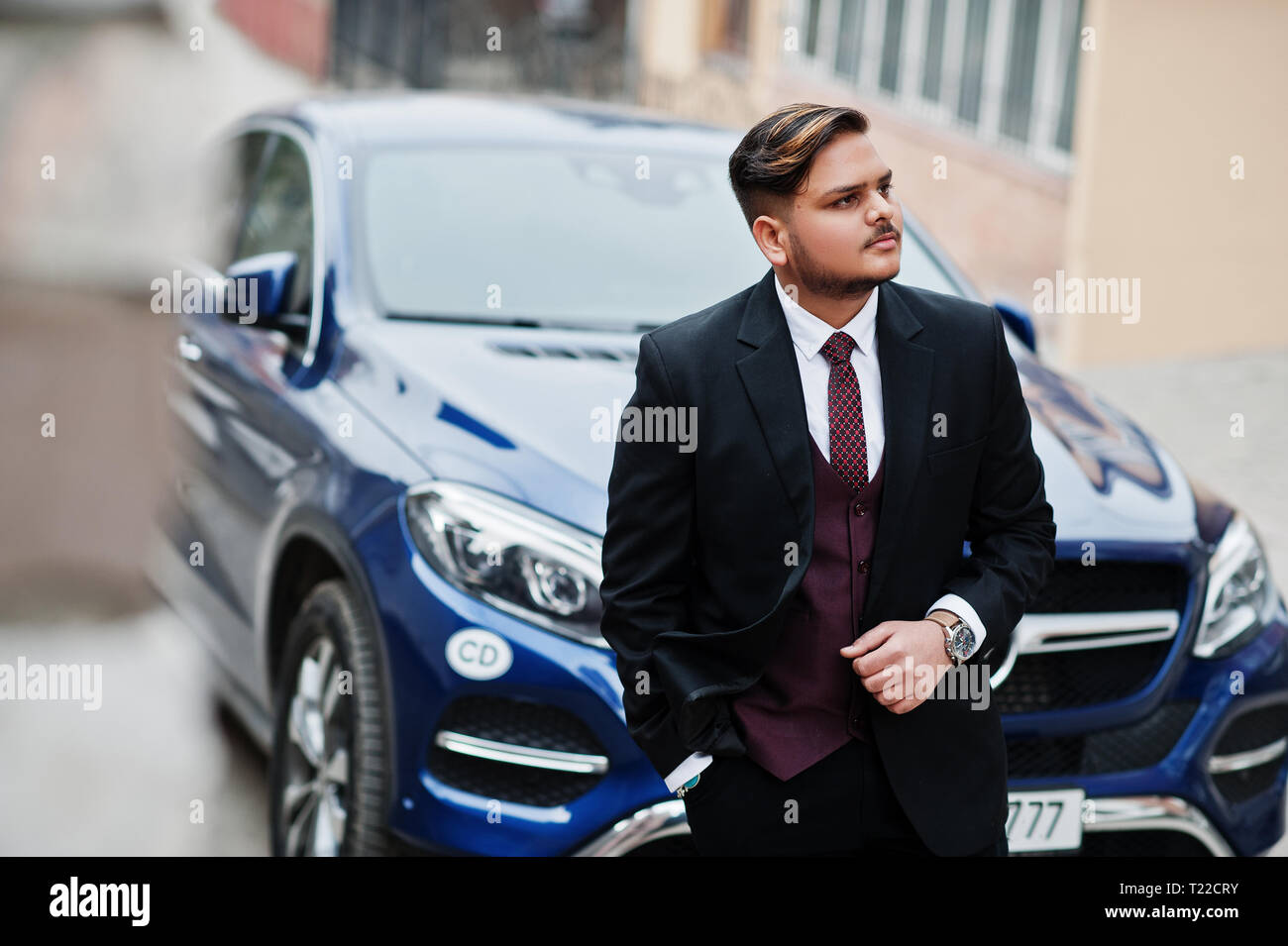 Rich indian businessman in formal wear standing against business suv ...
