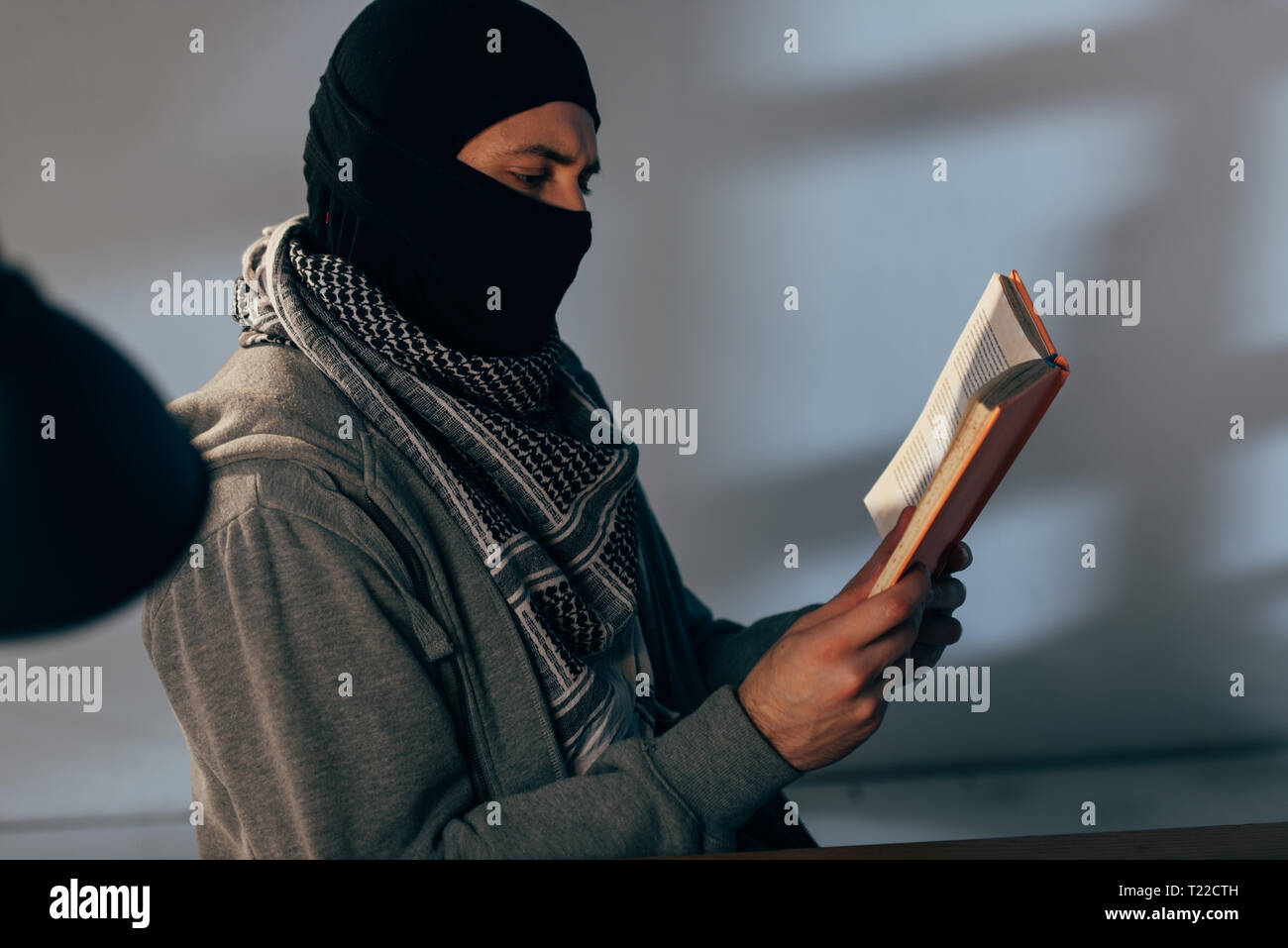 Terrorist in black mask and keffiyeh scarf reading book Stock Photo - Alamy