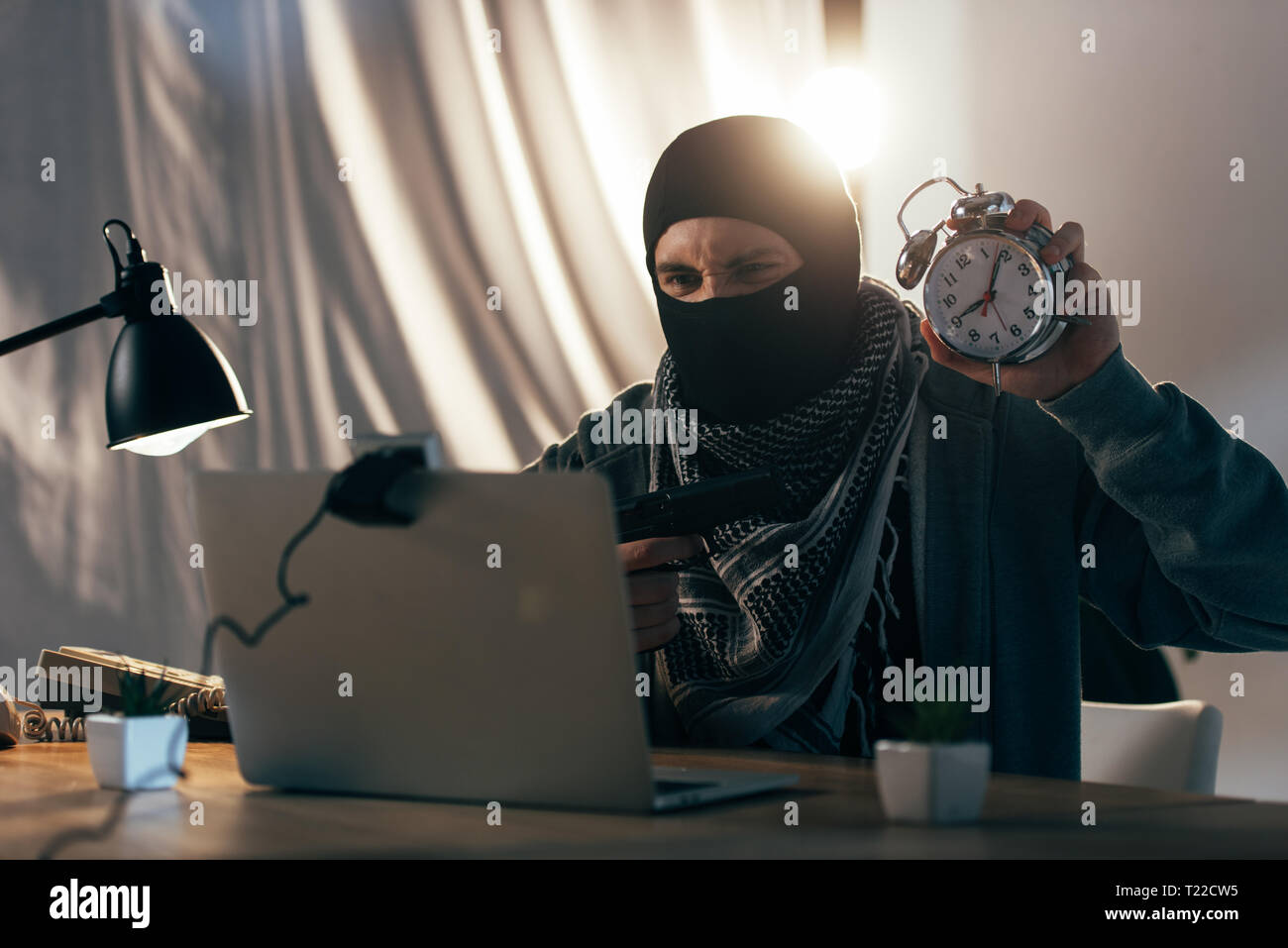 Angry terrorist with gun showing alarm clock at webcam Stock Photo - Alamy