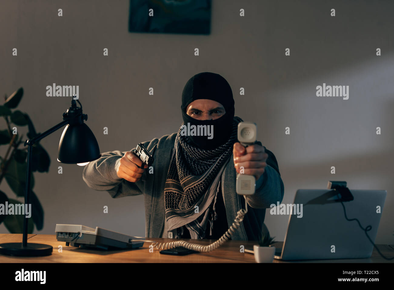 Aggressive terrorist in mask holding handset and aiming gun Stock Photo ...