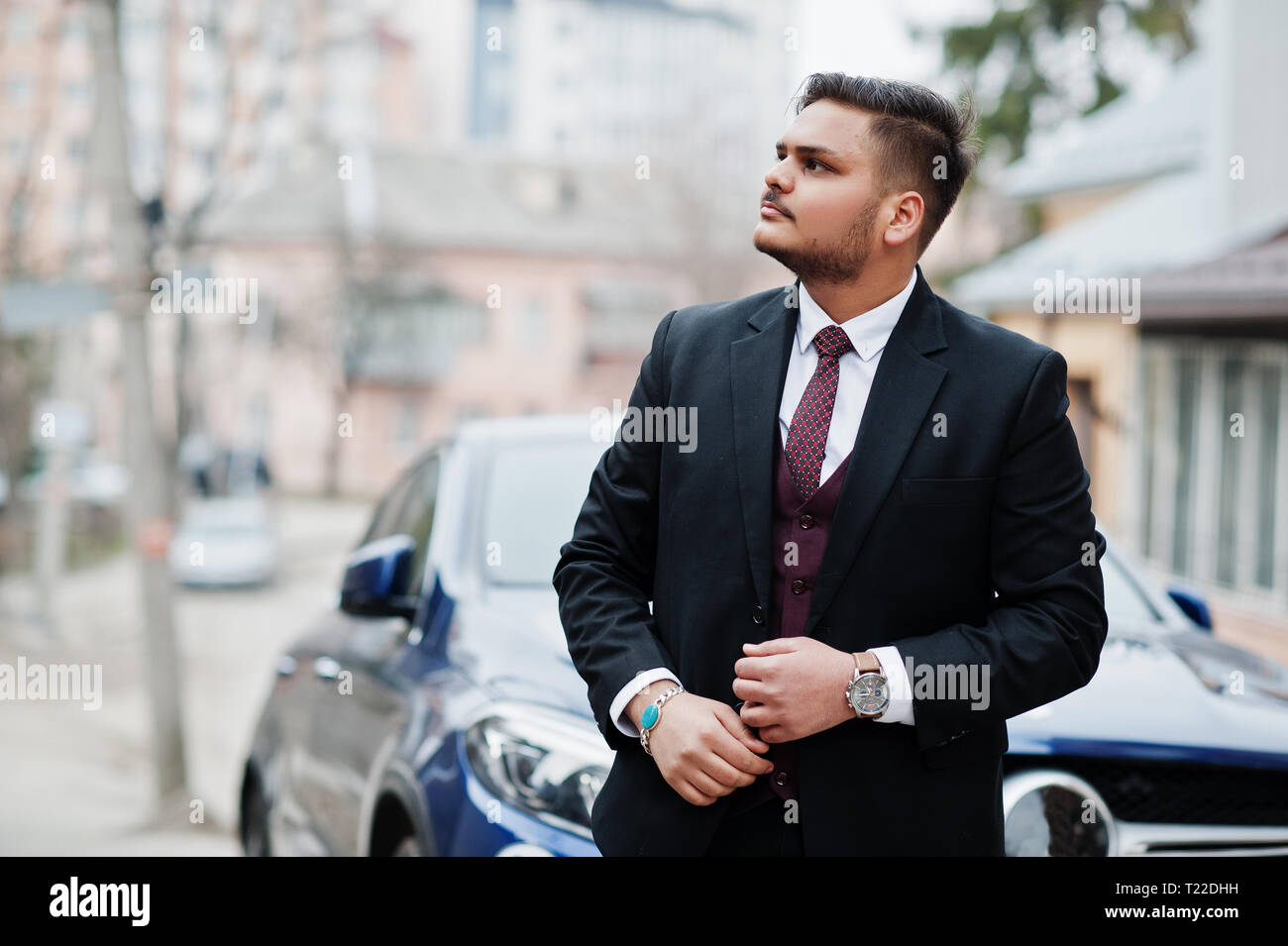Rich indian businessman in formal wear standing against business suv ...