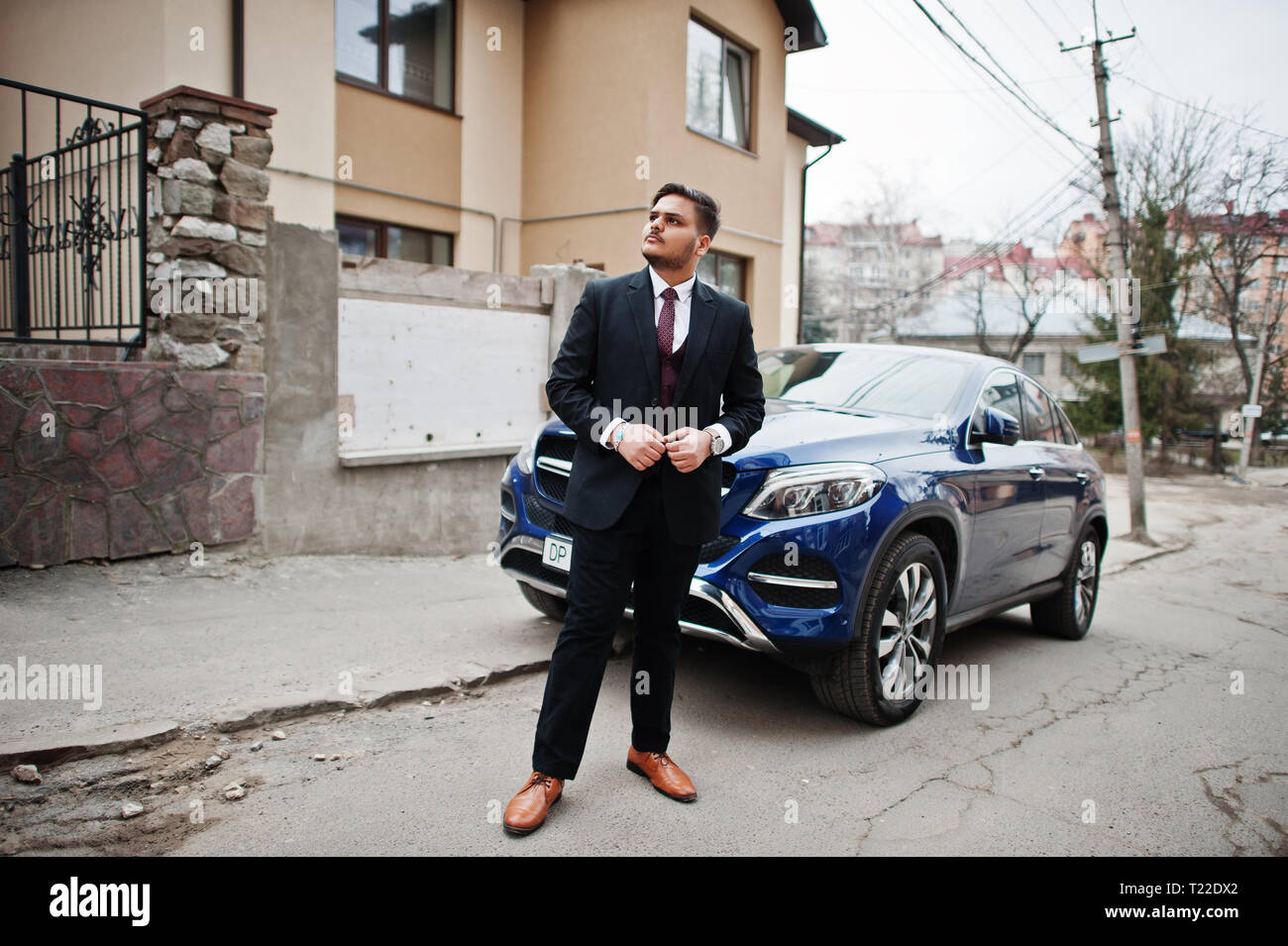 Rich indian businessman in formal wear standing against business suv ...