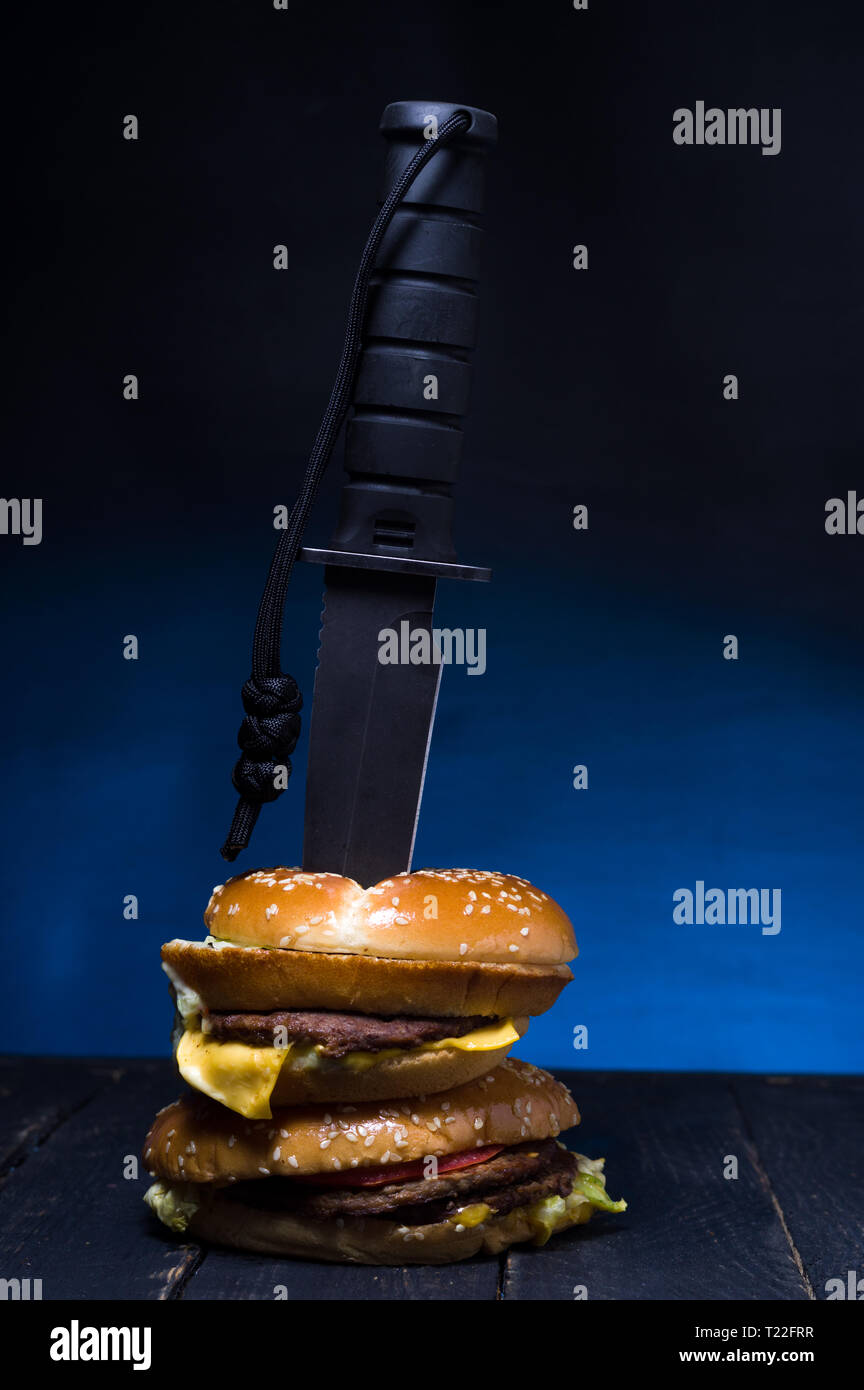 A large knife embedded in burgers. Double burger with meat. Vertical ...