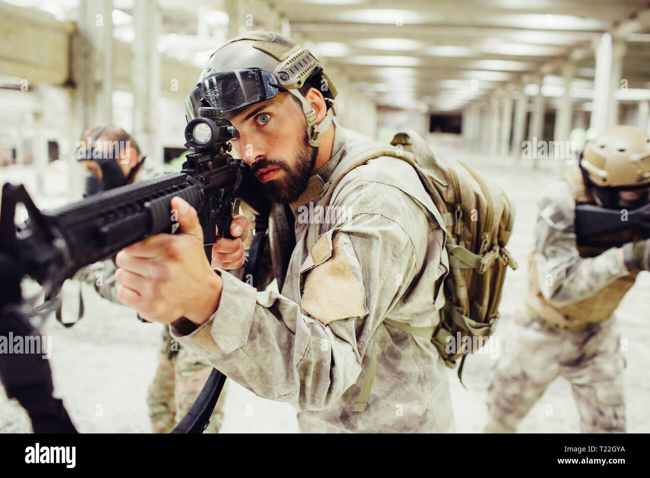 Brave and serious soldier is standing with his combads in a bright and ...