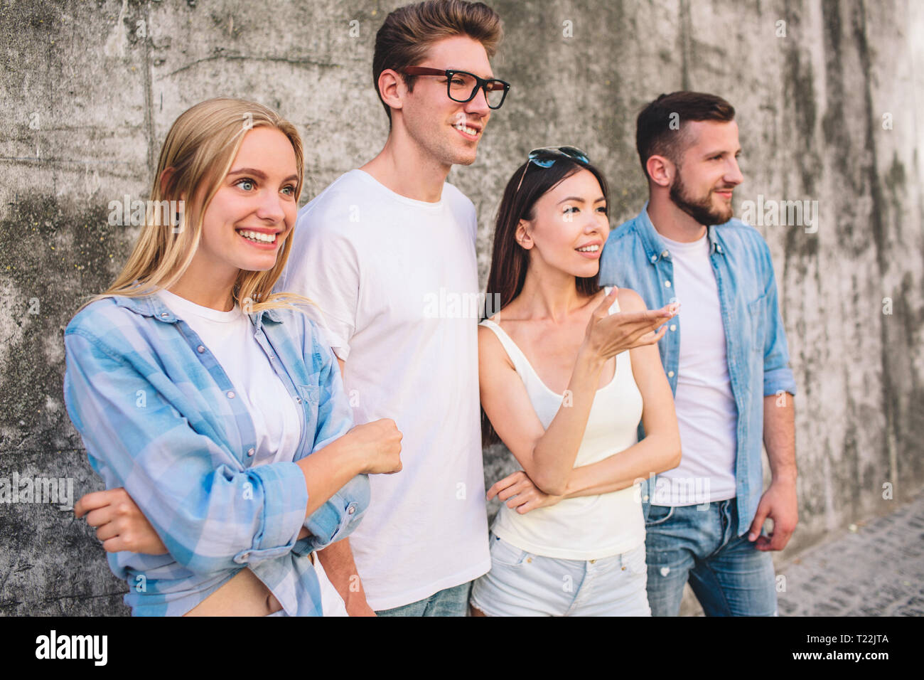 Young and fearless people are standing on grey background and loking ...
