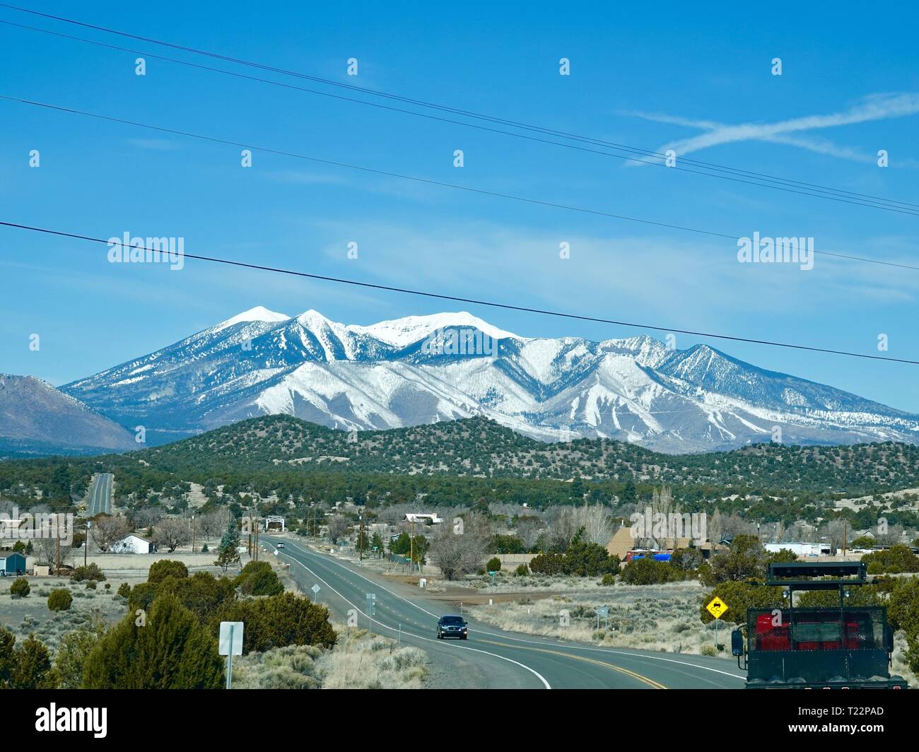 Highway, hilly road, with snow topped Arizona Peaks in the background ...