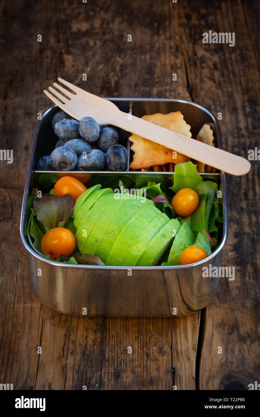 Lunch box of leaf salad, avocado, blueberries, tomatoes and crackers ...