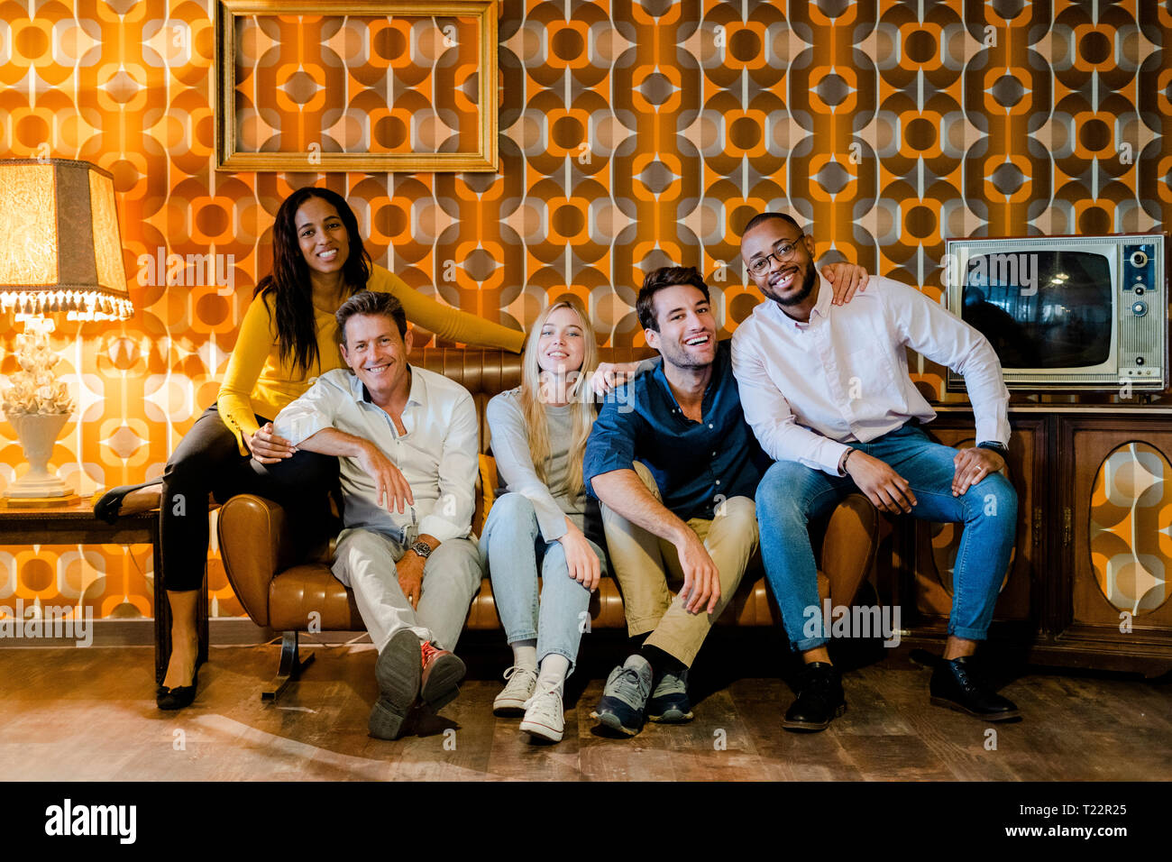 Group of smiling people sitting on couch in vintage living room Stock ...