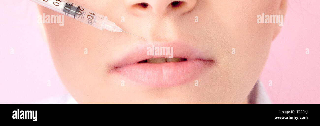 Doctor in gloves giving woman botox injections in lips, on pink ...