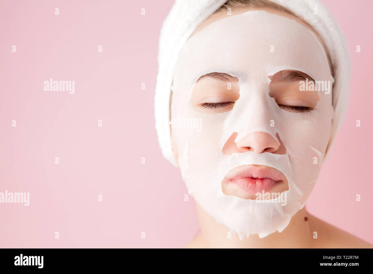 Beautiful young woman is applying a cosmetic tissue mask on a face on a ...