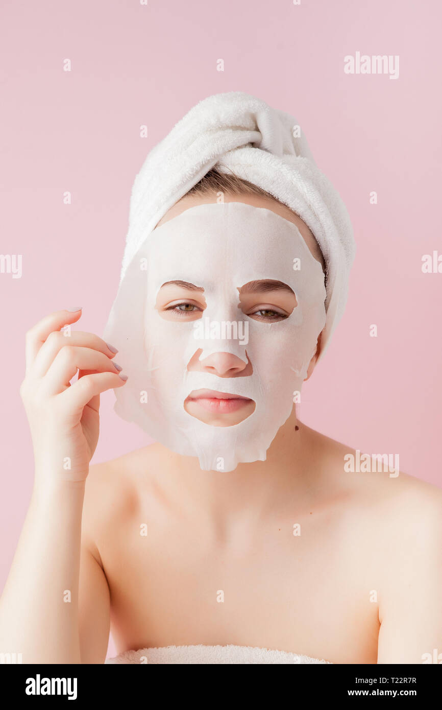 Beautiful young woman is applying a cosmetic tissue mask on a face on a ...