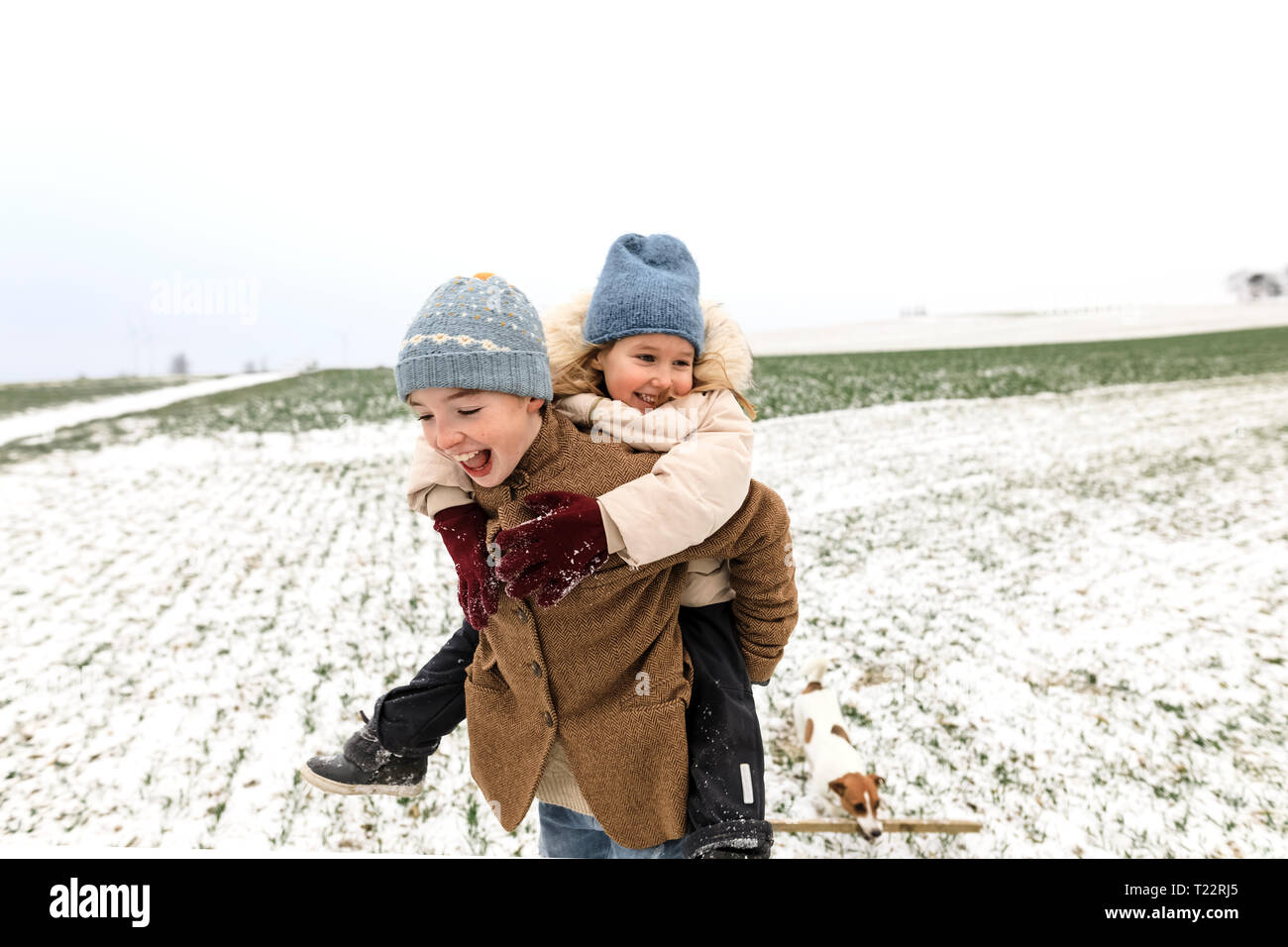 Boy carrying happy sister piggyback in winter landscape Stock Photo - Alamy