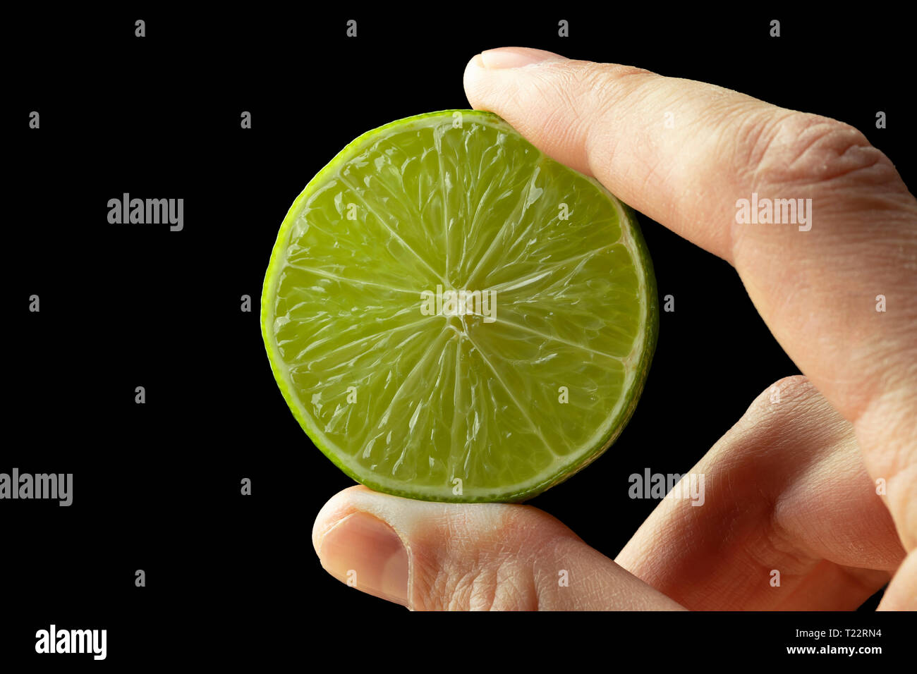 Half lime in the hand of a man. Isolate on black background Stock Photo ...