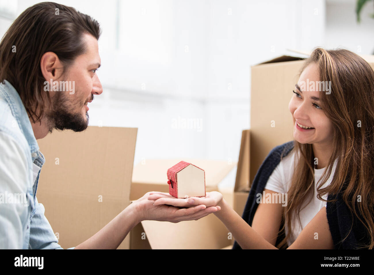 Man handing over tiny house model to girlfriend surrounded by cardboard ...