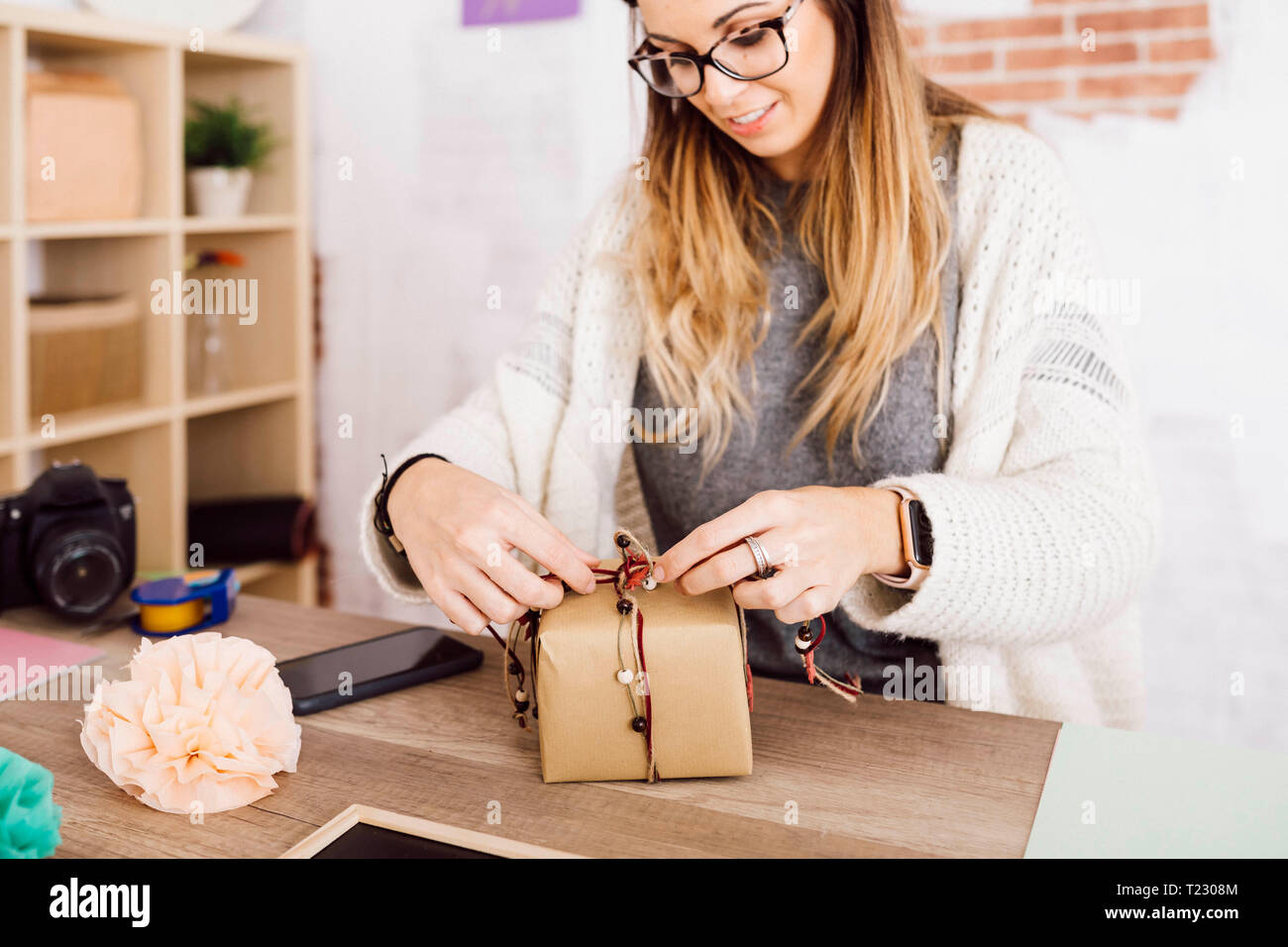 Young woman wrapping a gift in her studio Stock Photo - Alamy