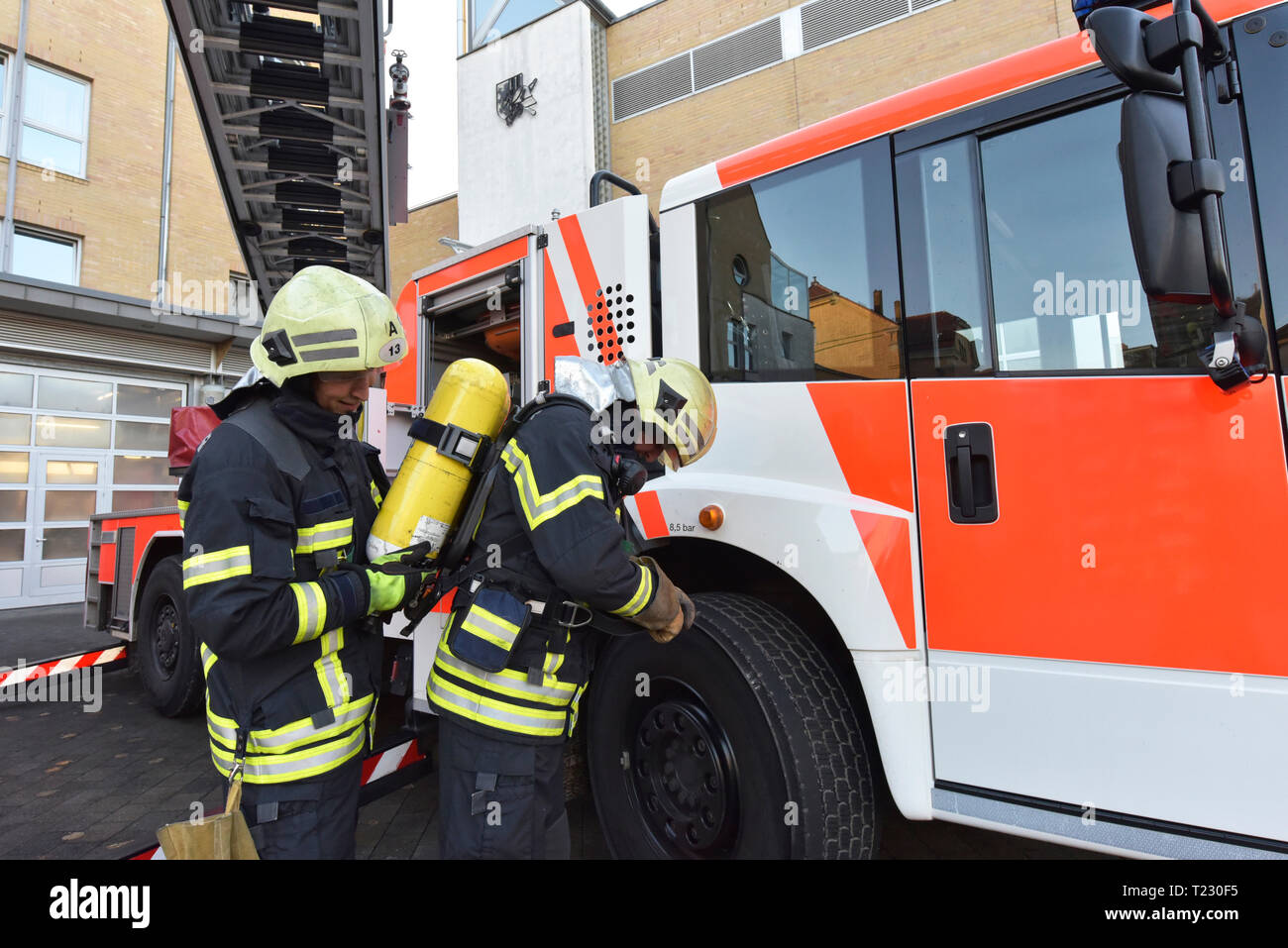 Two firefighters at fire engine preparing for an operation Stock Photo ...