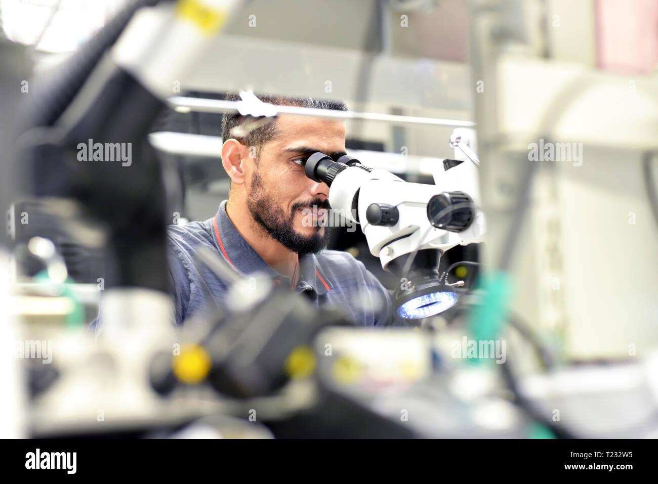 Man using a microscope for the quality control in the manufacturing of ...