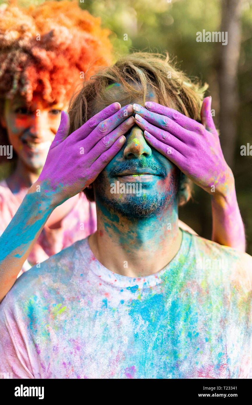 Affectionate couple celebrating Holi, Festival of Colors, woman covring ...