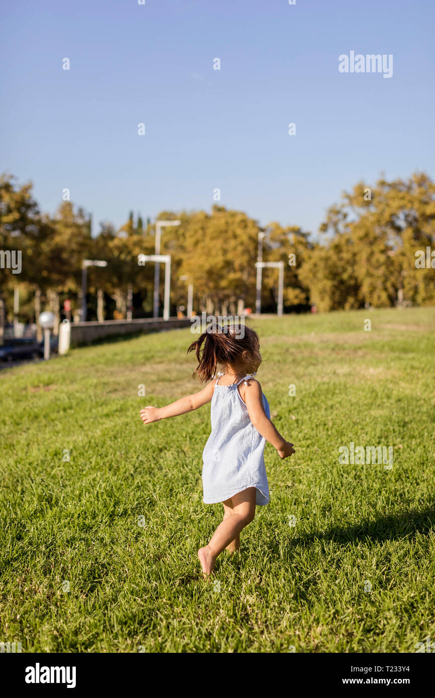 Rear view of little girl running on lawn in apark Stock Photo - Alamy