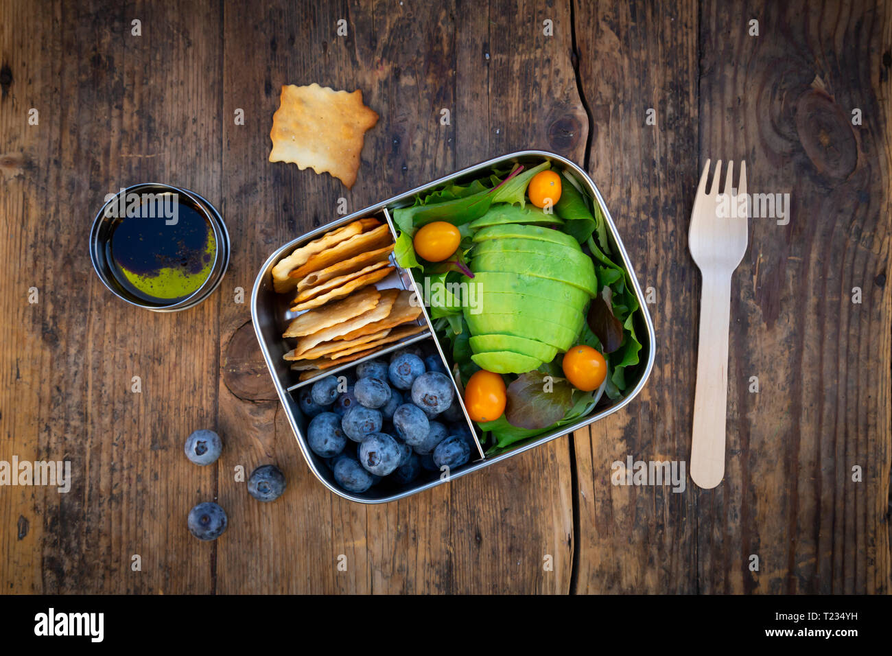 Lunch box of leaf salad, avocado, blueberries, tomatoes and crackers ...