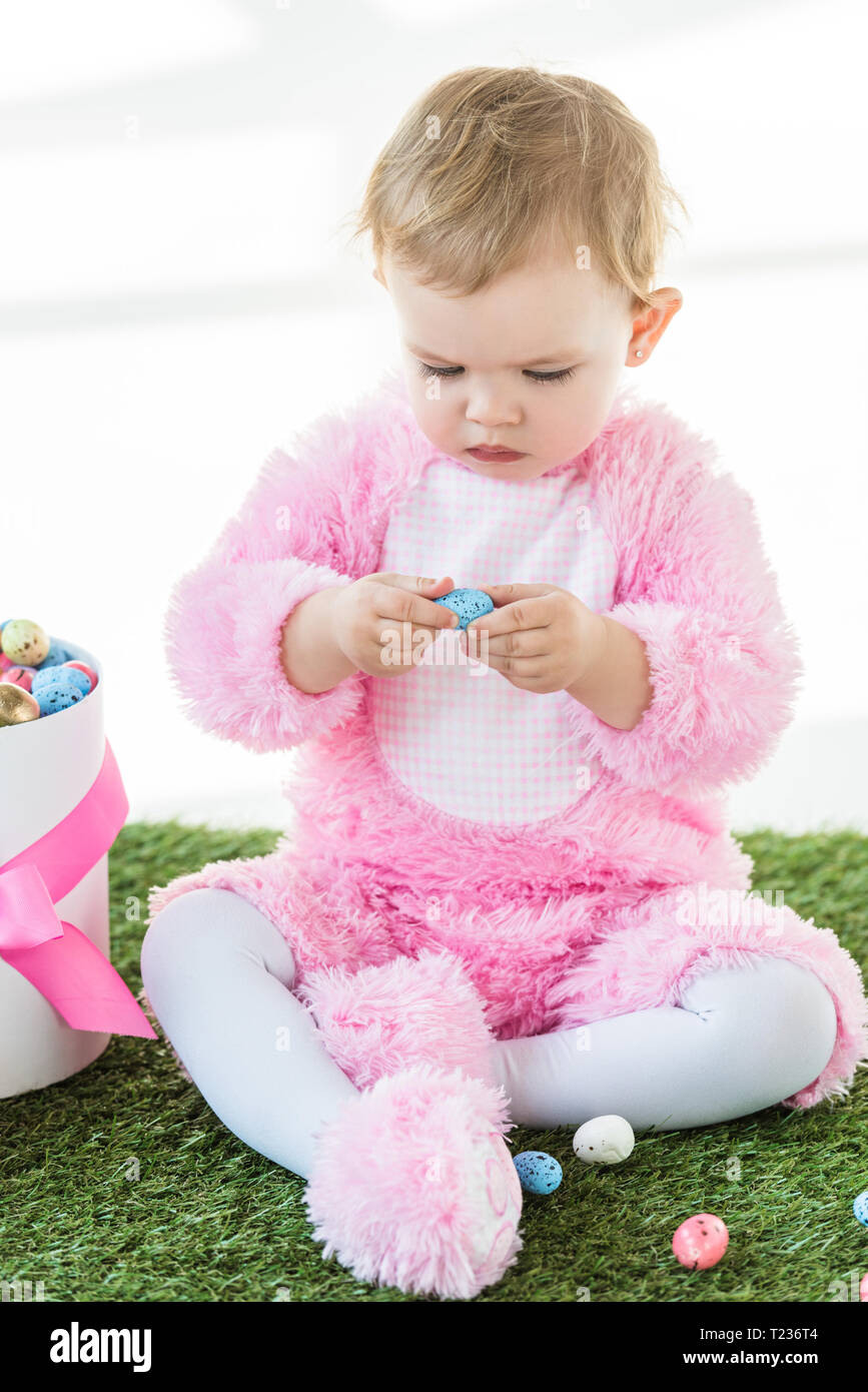 cute kid in pink fluffy costume holding blue quail egg while sitting ...