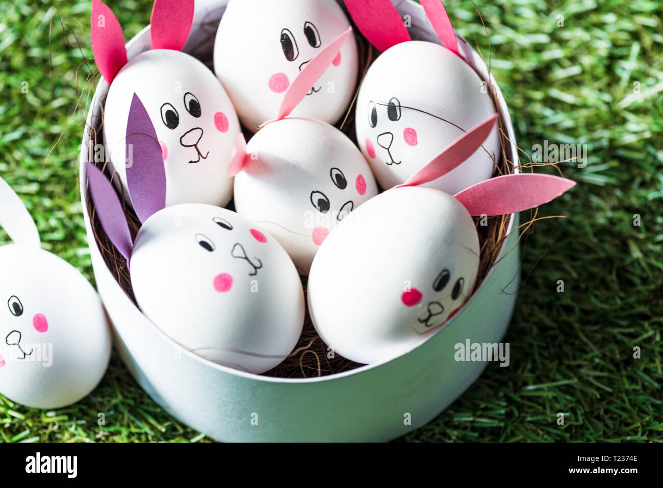 box with white chicken eggs with drawn rabbit faces and paper ears on ...
