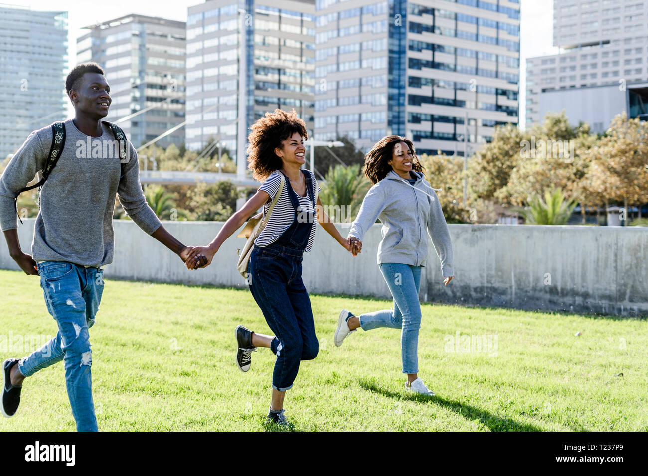Three friends running lawn city hi-res stock photography and images - Alamy