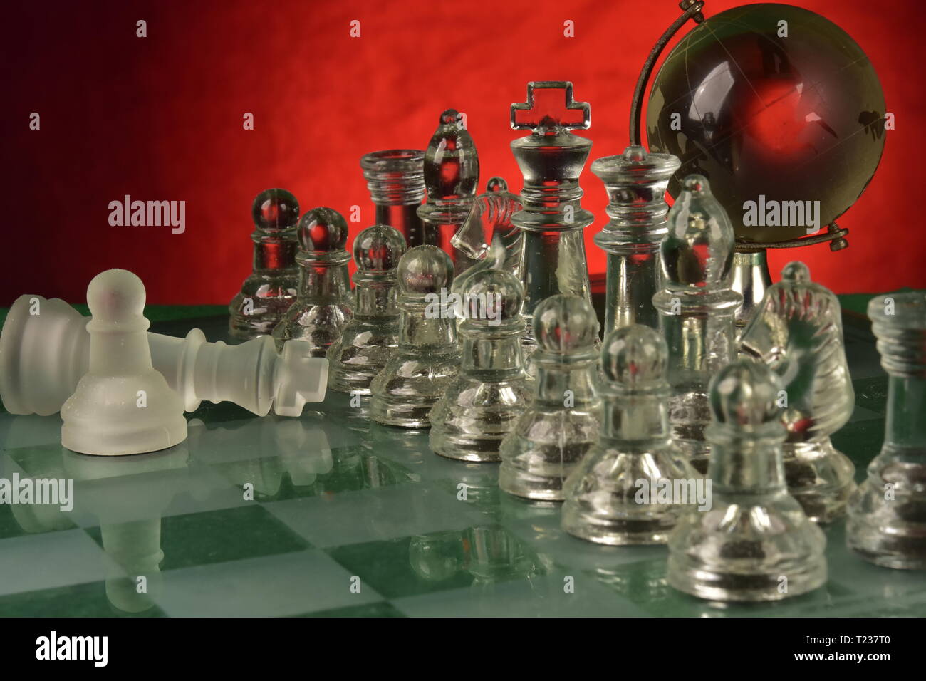 Chessboard table with glass pieces and red background Stock Photo - Alamy