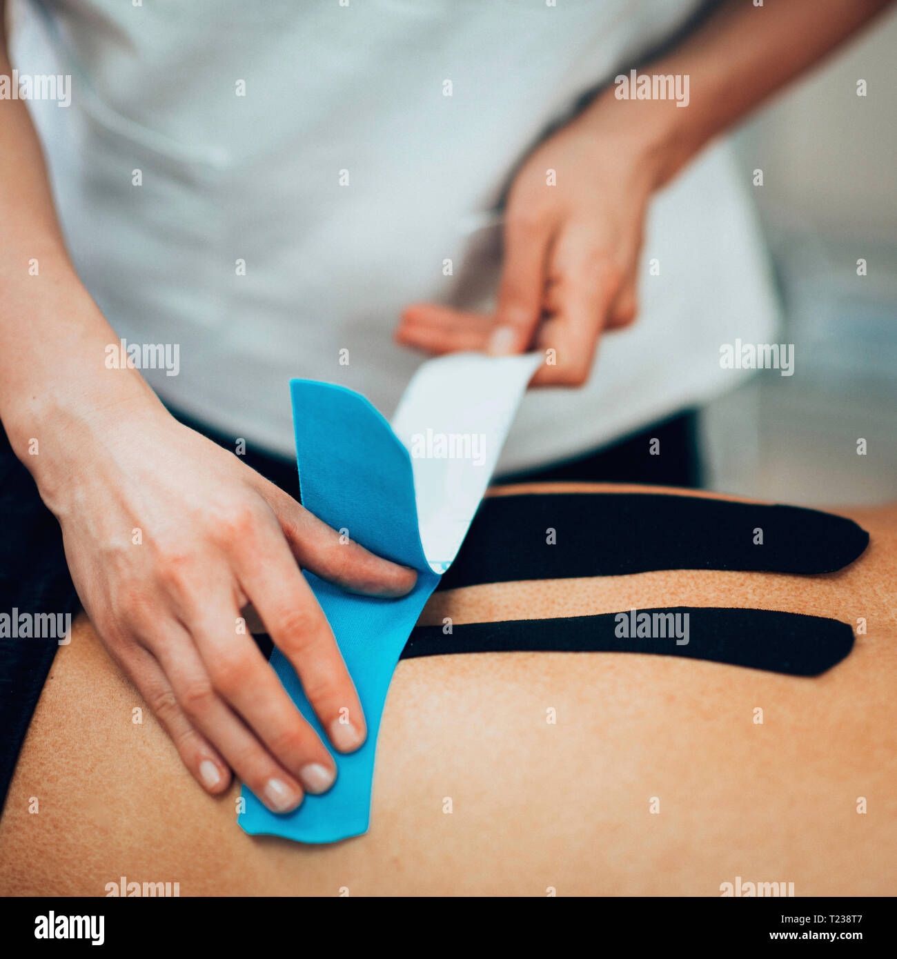 Physical therapist placing kinesio tape on patient's back Stock Photo - Alamy
