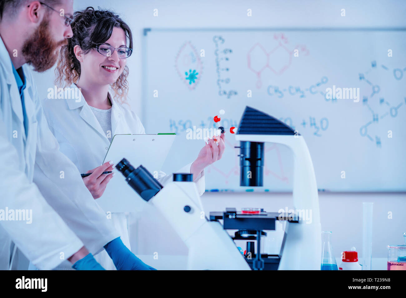 Young scientist smiling and standing in front of the microscope in ...