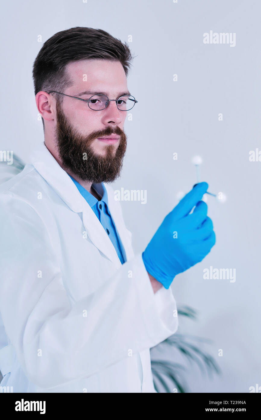 Portrait of male researcher wearing white coat in laboratory, holding ...
