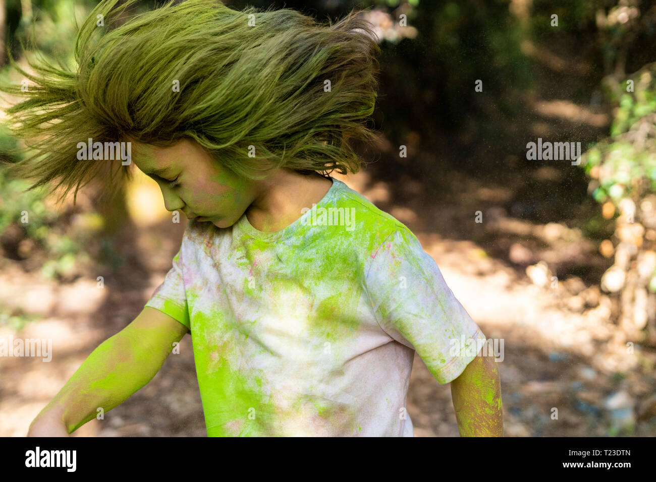 Boy shaking his head, full of colorful powder paint, celebrating Holi ...