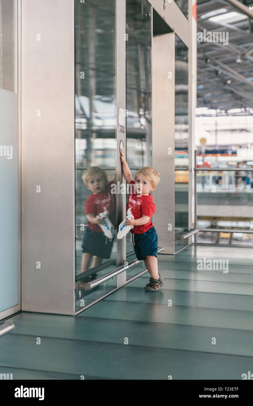 Little boy pushing elevator button at the airport Stock Photo - Alamy