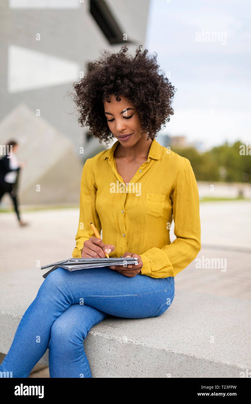 Woman sitting on bench taking notes Stock Photo - Alamy