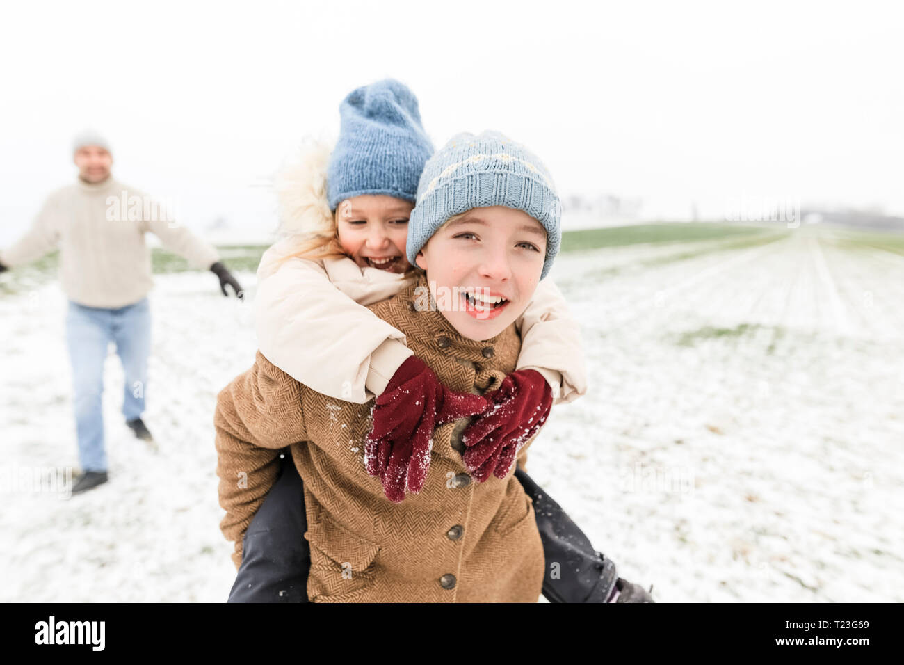 Boy carrying happy sister piggyback in winter landscape Stock Photo - Alamy