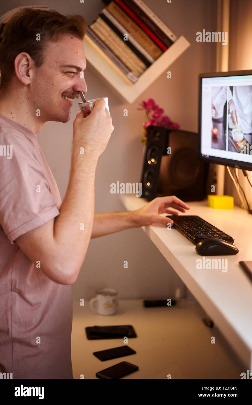 one young man, 20-25 years old, using computer, with standing desk ...