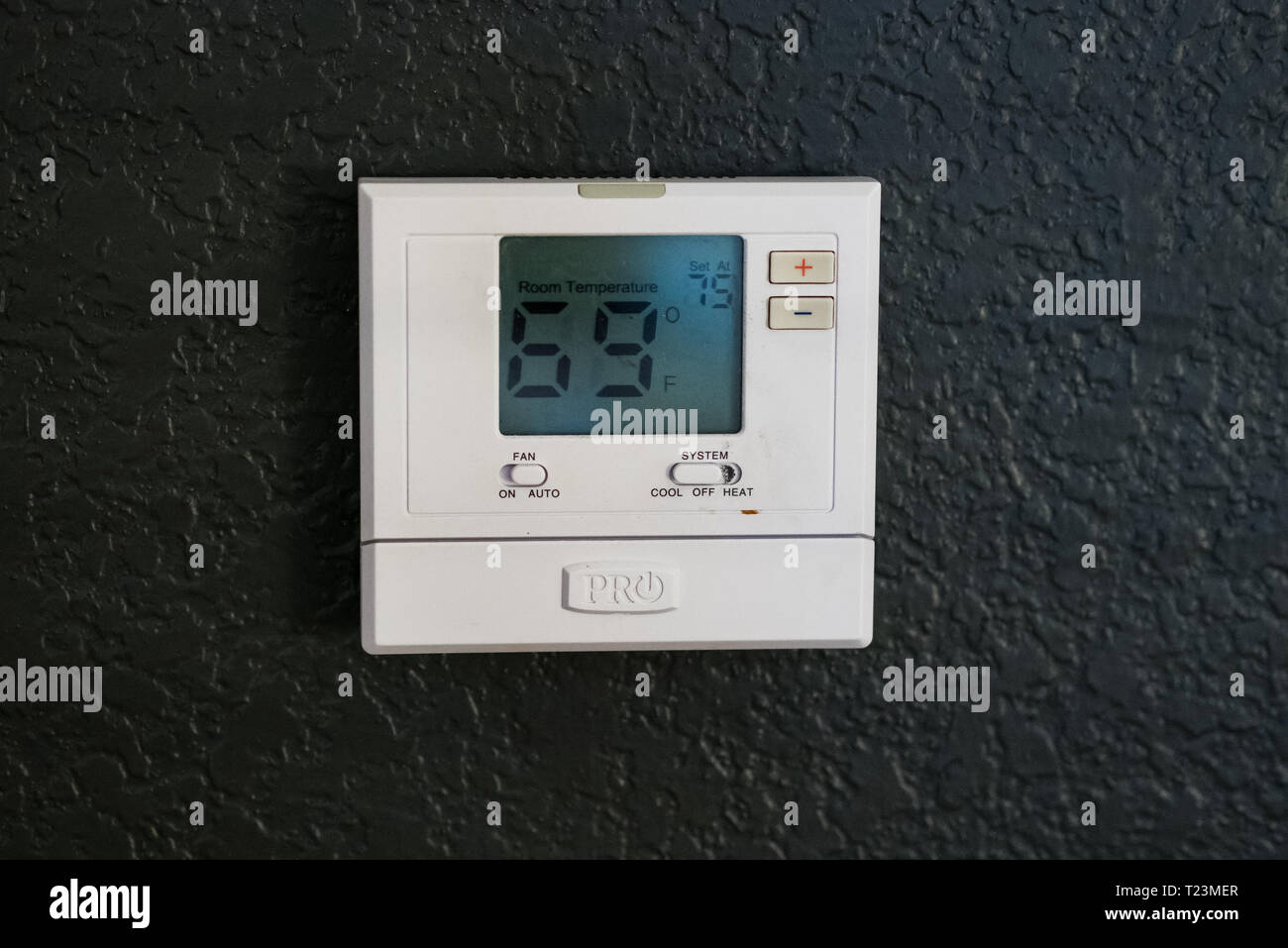 thermostat mounted on a dark grey wall showing 69 degree fahrenheit ...