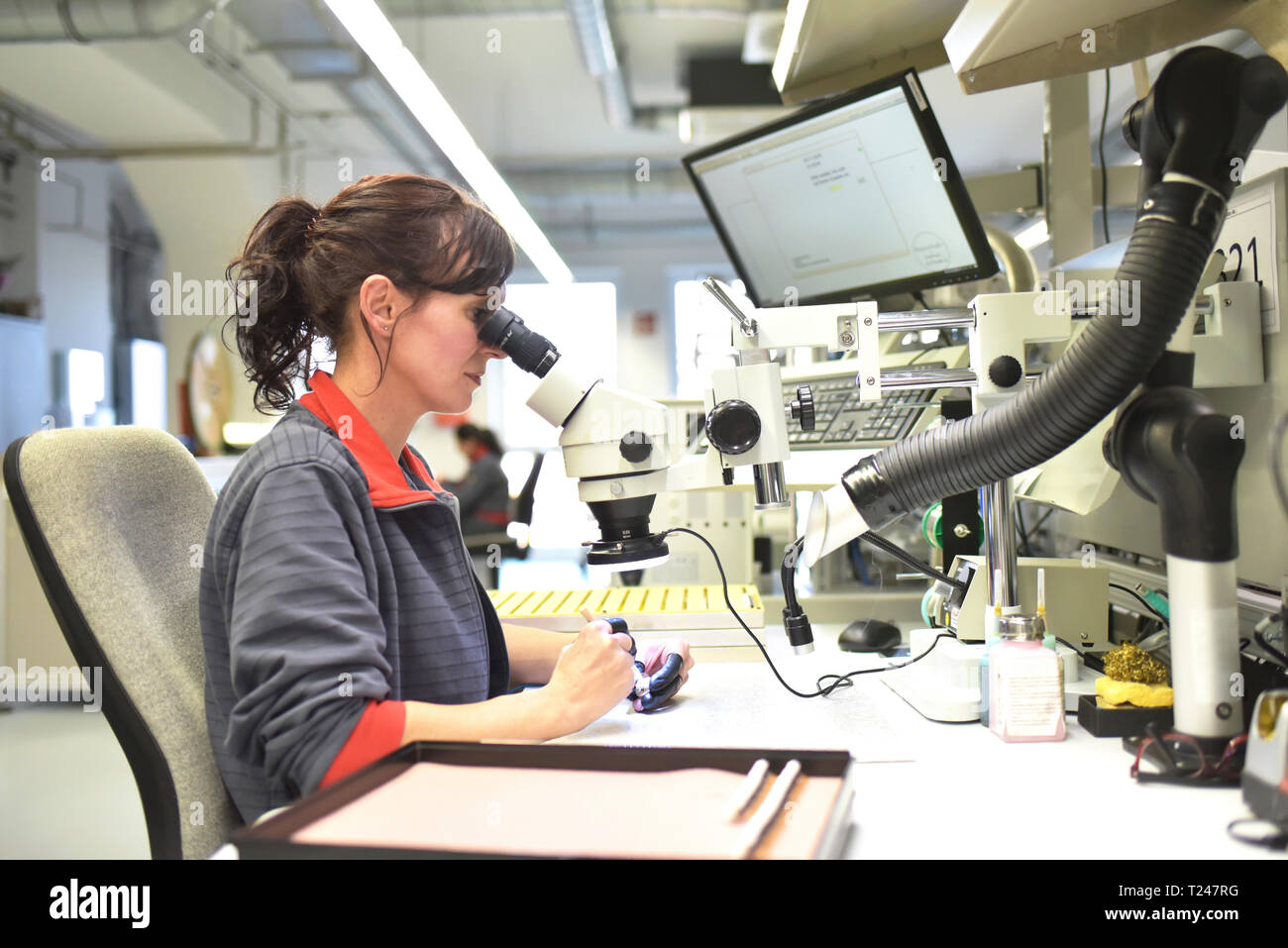 Woman using a microscope for the quality control in the manufacturing ...