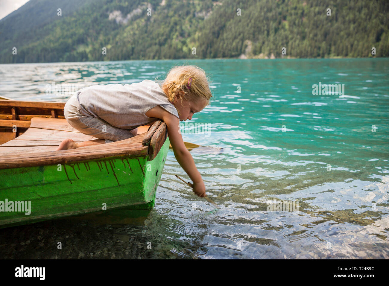Austria, Carinthia, Weissensee, girl in rowing boat putting a stick in ...