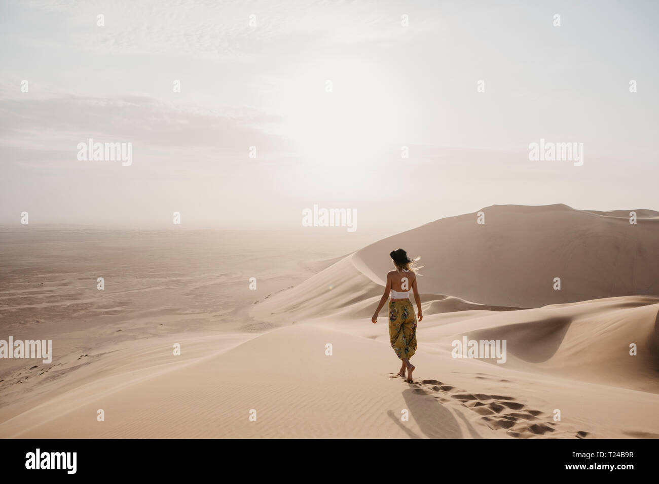 Namibia, Namib, back view of woman walking barefoot on desert dune ...