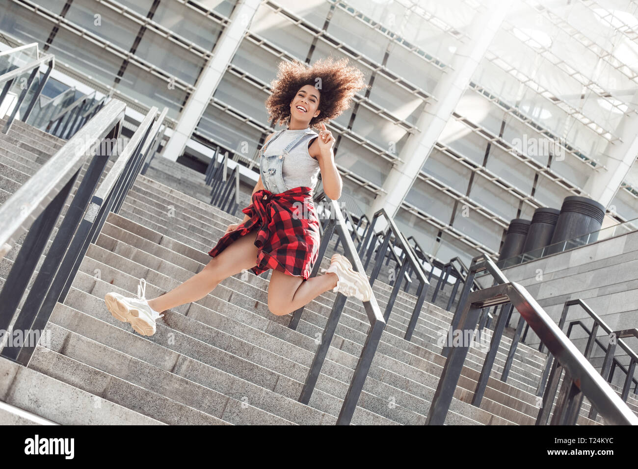 Young stylish woman in the city street jumping on concrete stairs ...