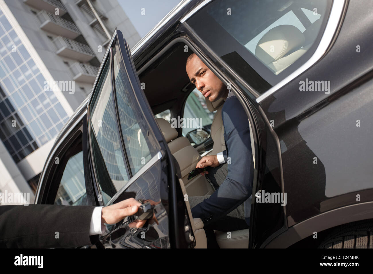 Security guard opening door young mulatto businessman sitting in the ...